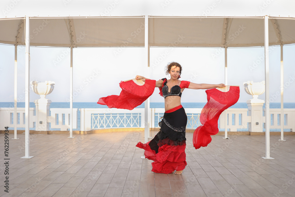 beautiful dancer woman in black and red suit with fan dancing on ...