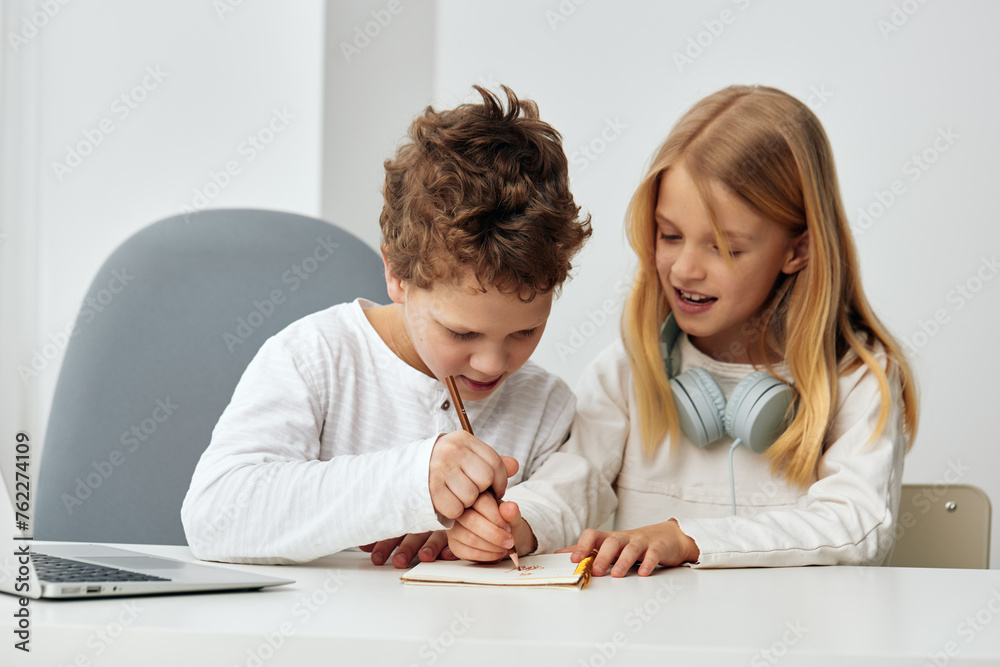 Young boy and girl happily studying together at home on a laptop for ...