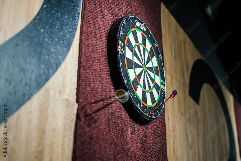 The dartboard is a focal point on the wall, with colorful darts missing ...