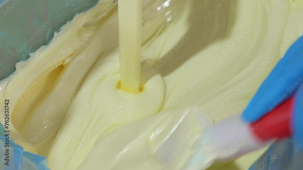 Close Up Of Yellow Liquid Butter Pouring Into Container. Worker Mixes ...