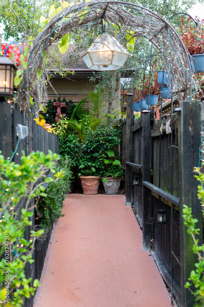 The back alley of a residential area with shrubs, flowers, arbor, clay ...