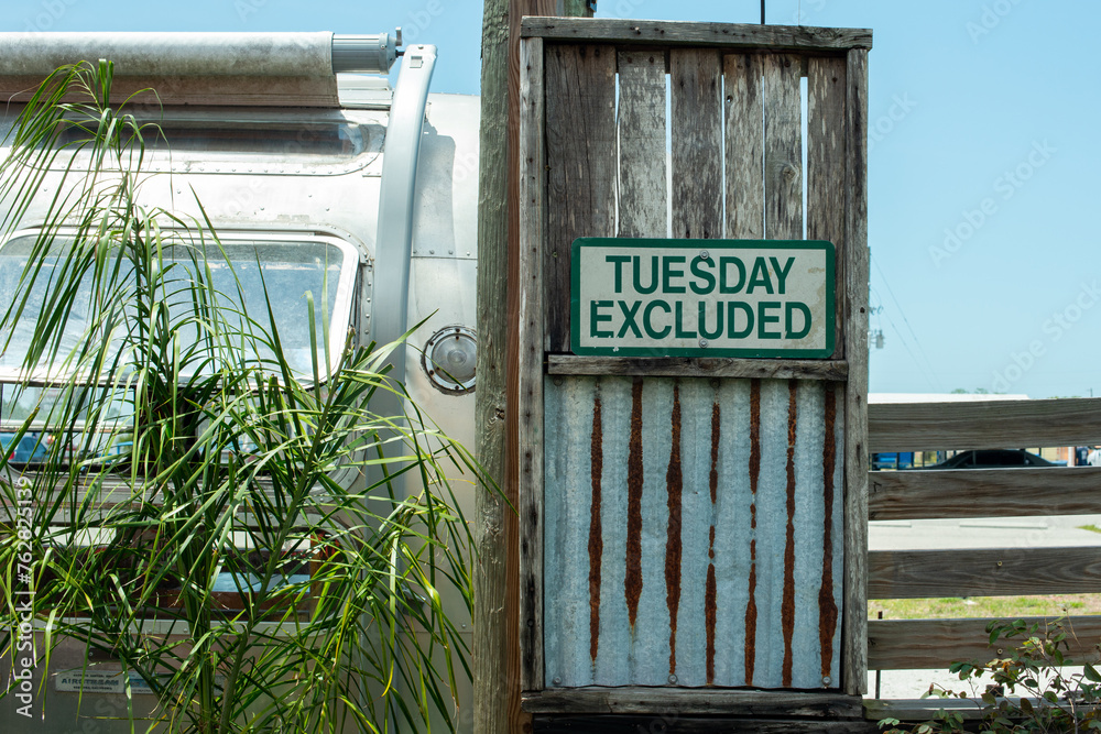 Tuesday excluded sign with green lettering and a cream colored ...