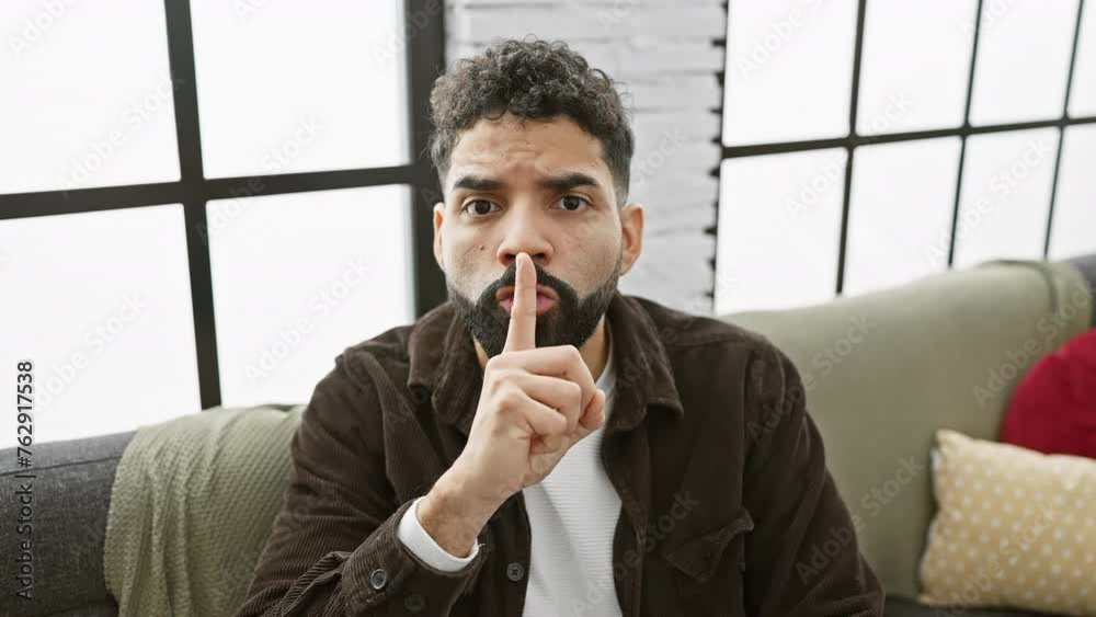 At home, a confident young man with a secret puts his finger to his ...
