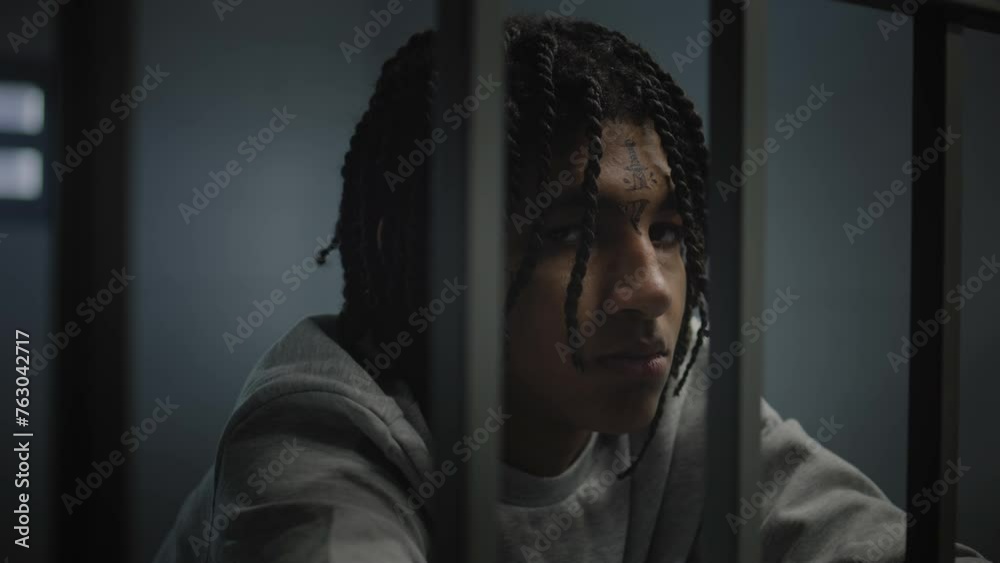 Angry African American teenage prisoner with face tattoos stands in ...