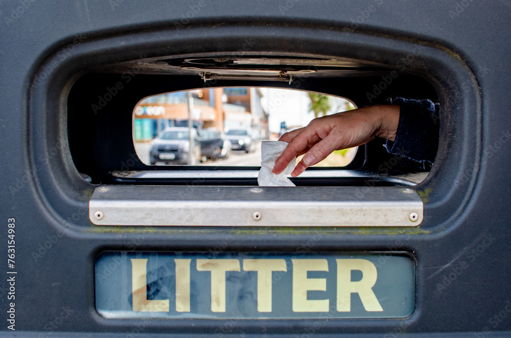 Litter, rubbish bin. Hand putting a used tissue into a collection bin ...