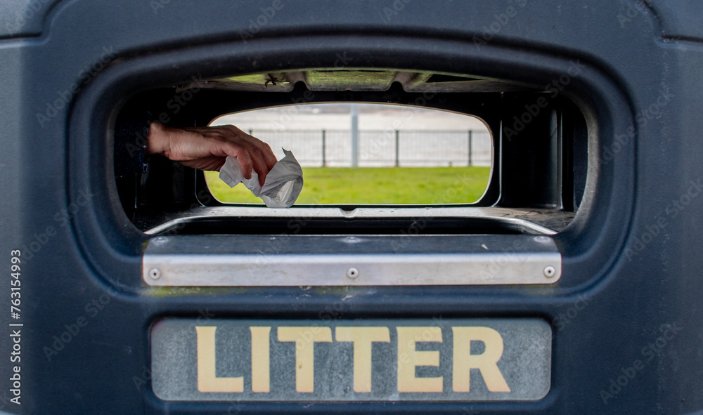 Litter, rubbish bin. Hand putting a used tissue into a collection bin ...