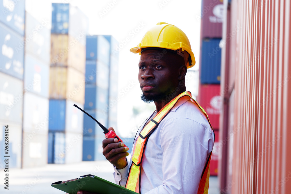 Engineer wearing safety helmet working in shipping container industry ...