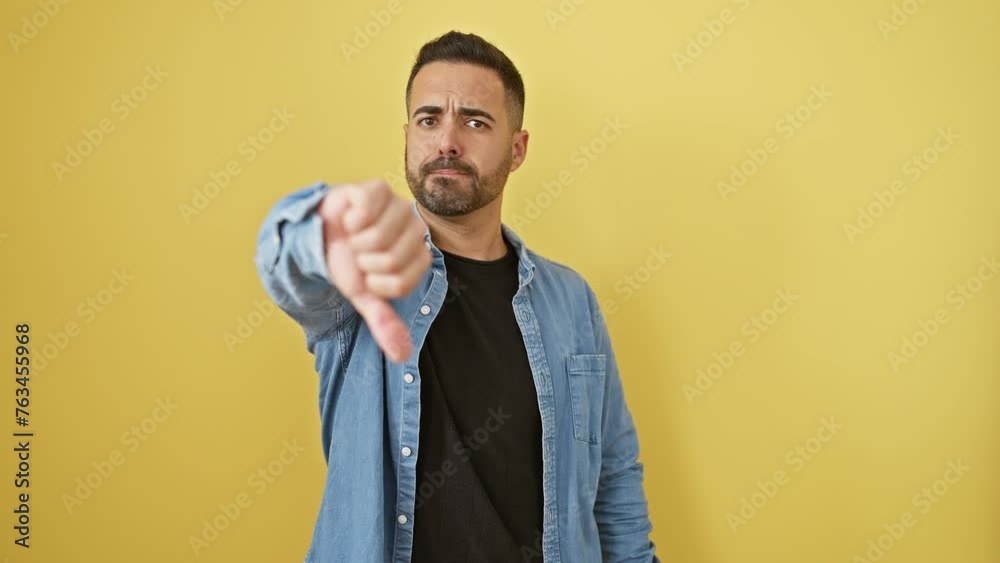 Angry young hispanic man, thumbs down sign of disapproval. wearing ...