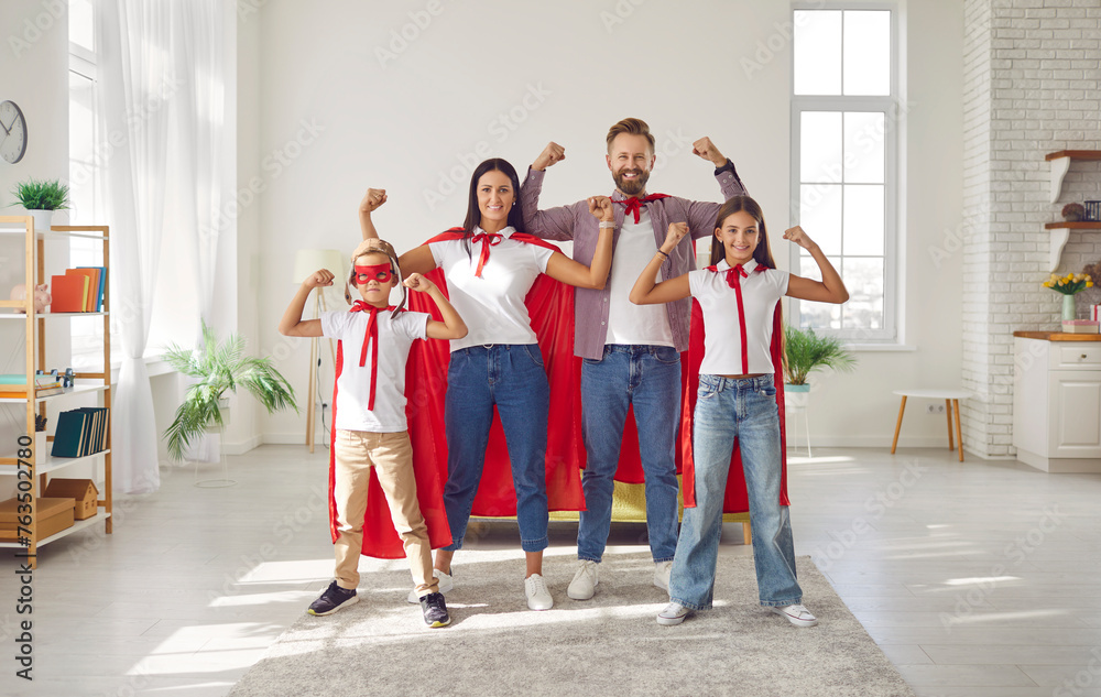 Funny happy family of four in superhero costumes standing with hands in ...