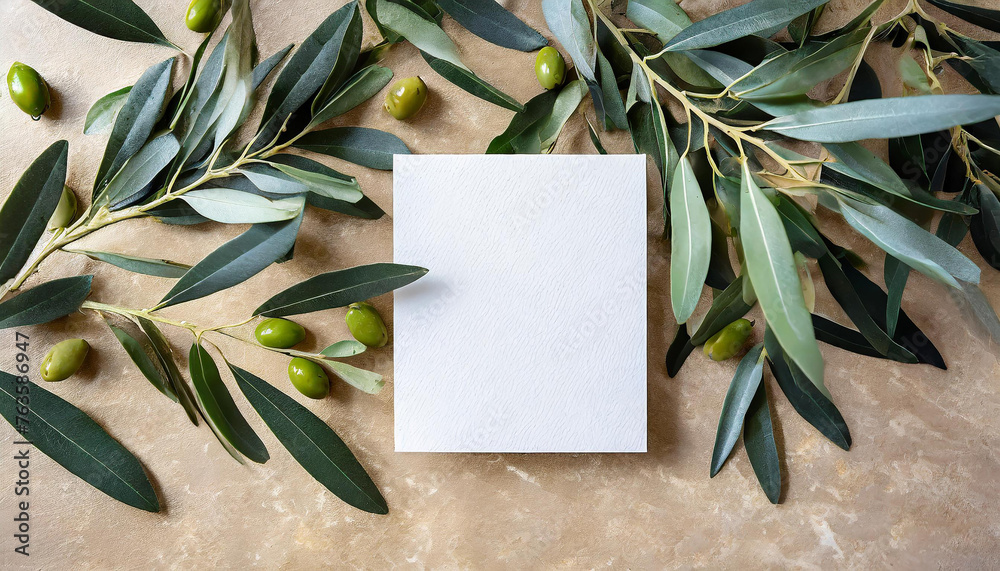 white paper card template on beige color table with olive tree leaf ...
