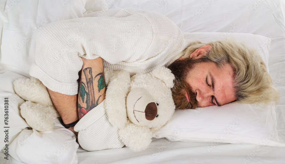 Bearded man sleeping at bedroom and hugging soft teddy bear. Handsome ...
