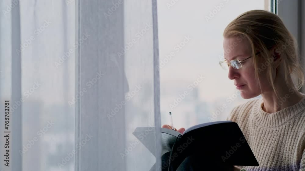 Inspired blonde writing her ideas. Content adult woman happily writes ...