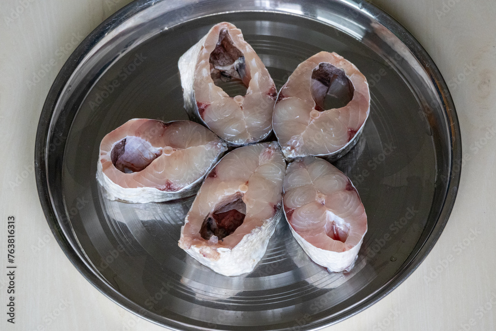 Raw Rui fish slice for cooking on a steel plate isolated on white ...