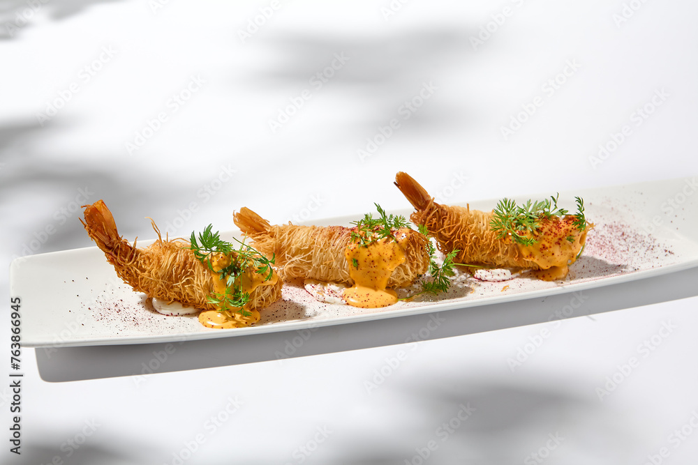 Traditional greek appetizer - kataifi wrapped shrimps on white plate ...