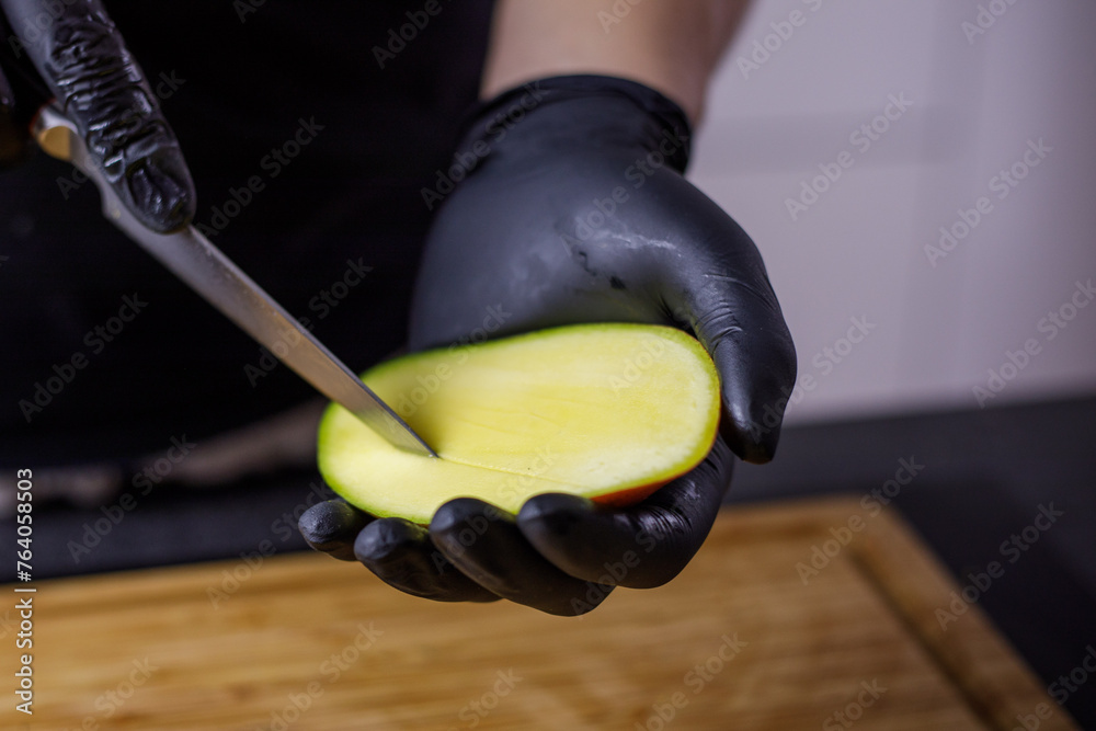 Person with black gloves cutting and slicing mango for smoothie wood ...
