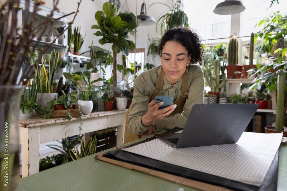 Small business owner using a laptop computer and her smartphone in her ...