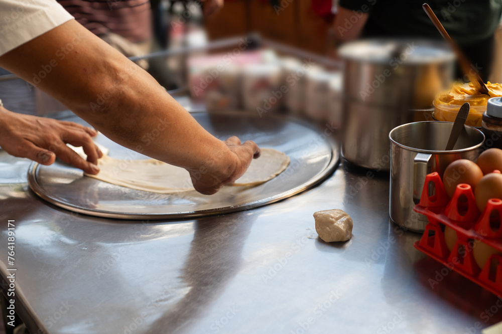 Foto de Man is spreading dough to make Roti Canai, Street food in ...