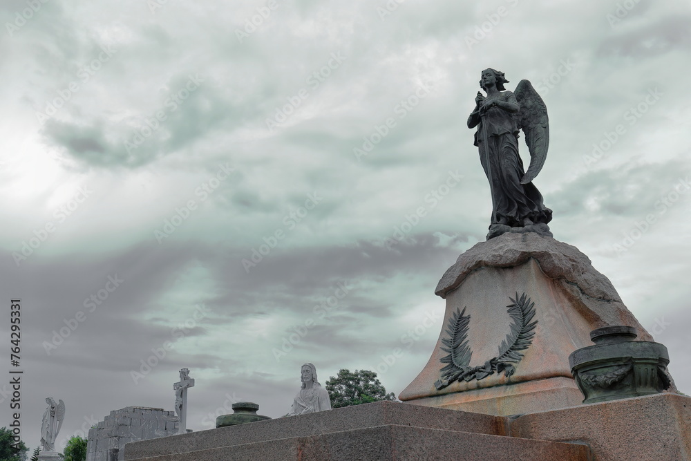 Sword-bearing angel and other statues peeking over graves on Avenida ...