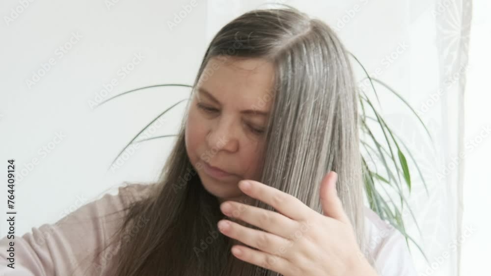 comb, brush in female hand, mature woman combing long brown hair ...
