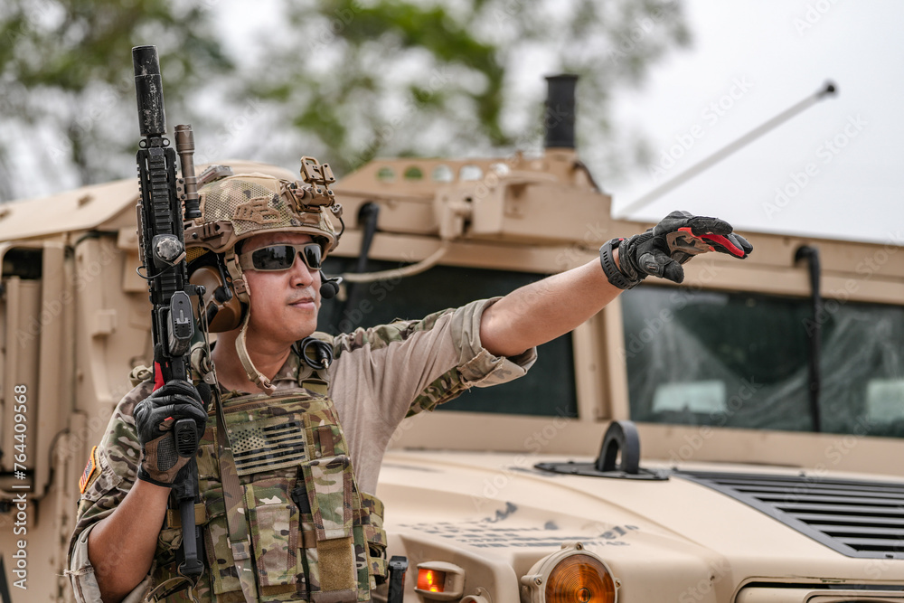 Confident soldier in full gear stands before a military vehicle, rifle ...