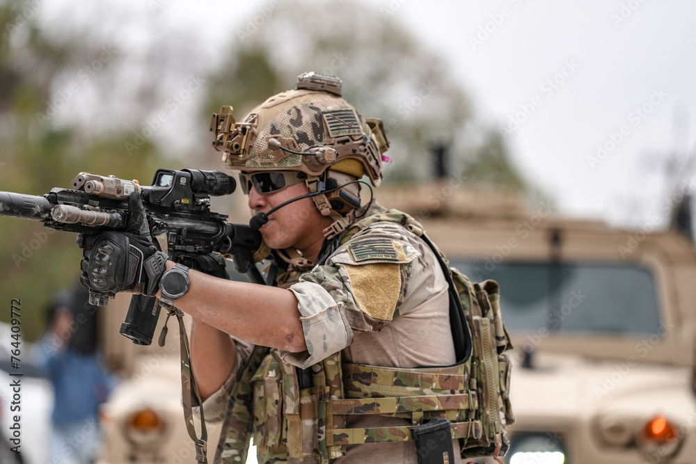 Confident soldier in full gear stands before a military vehicle, rifle ...