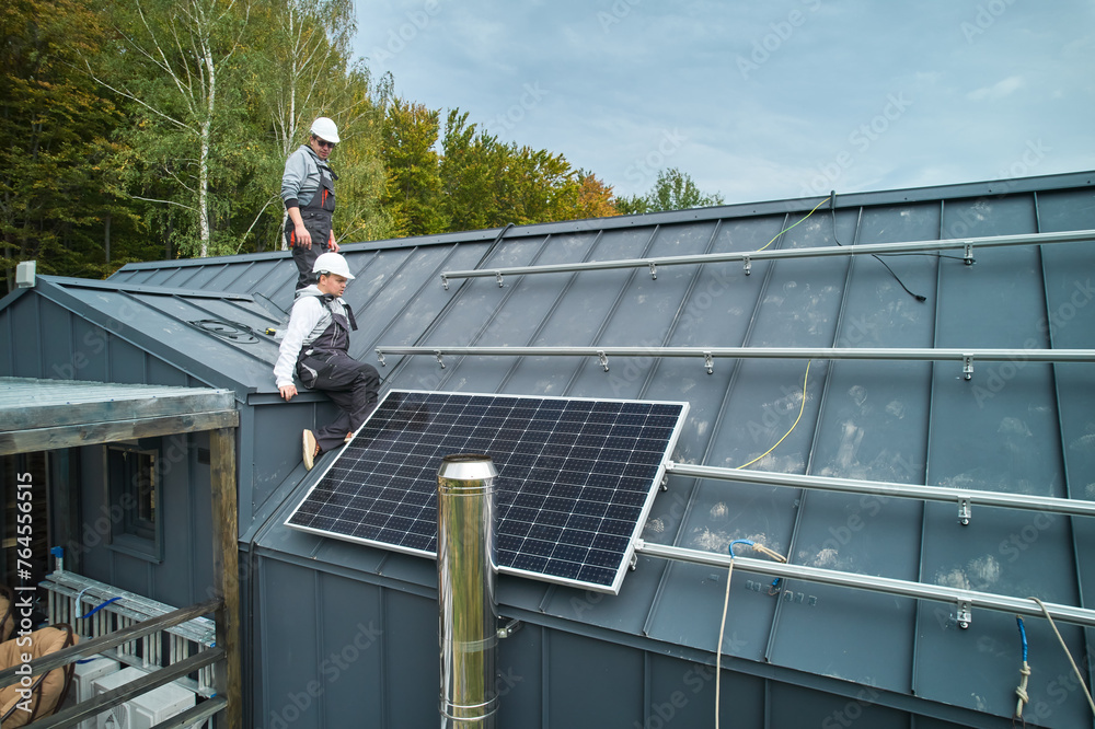 Men workers prepearing for mounting photovoltaic solar modules on roof ...