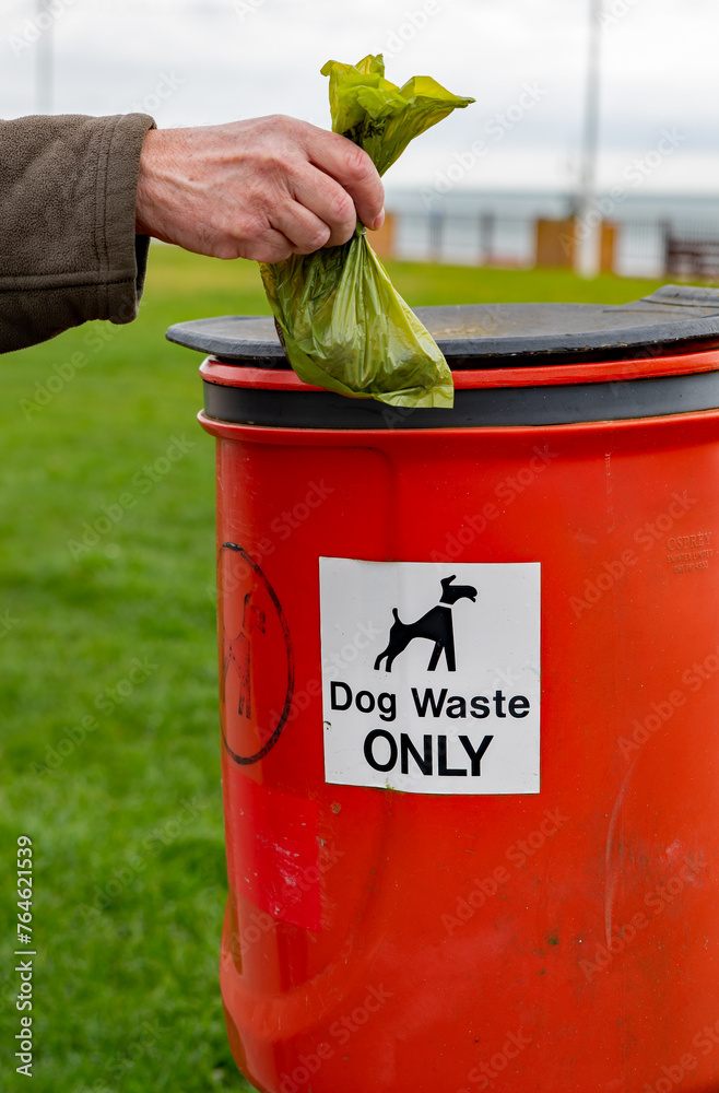 Dog poop bin. A hand placing a poo bag into a red waste bin for dog poo ... Dog poop bin. A hand placing a poo bag into a red waste bin for dog poo ...