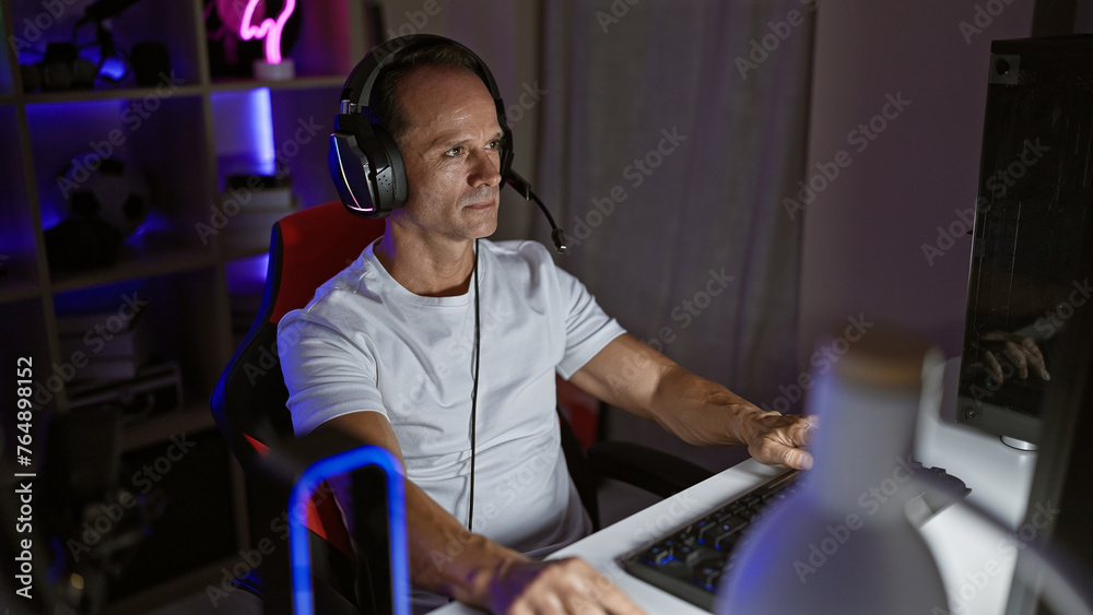 Handsome middle age man streaming video game at night, sitting ...