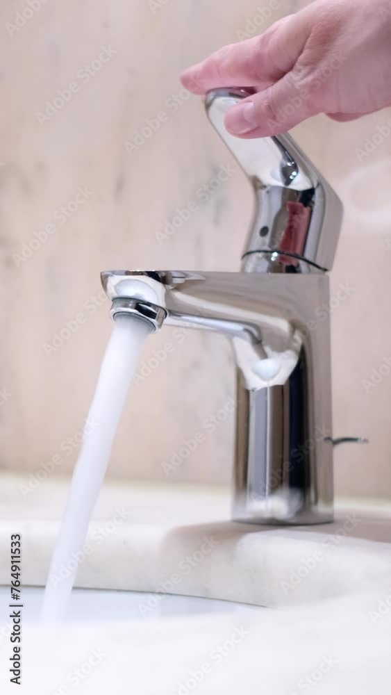 Close-up of caucasian female hand closing a mixer tap in a hotel ...