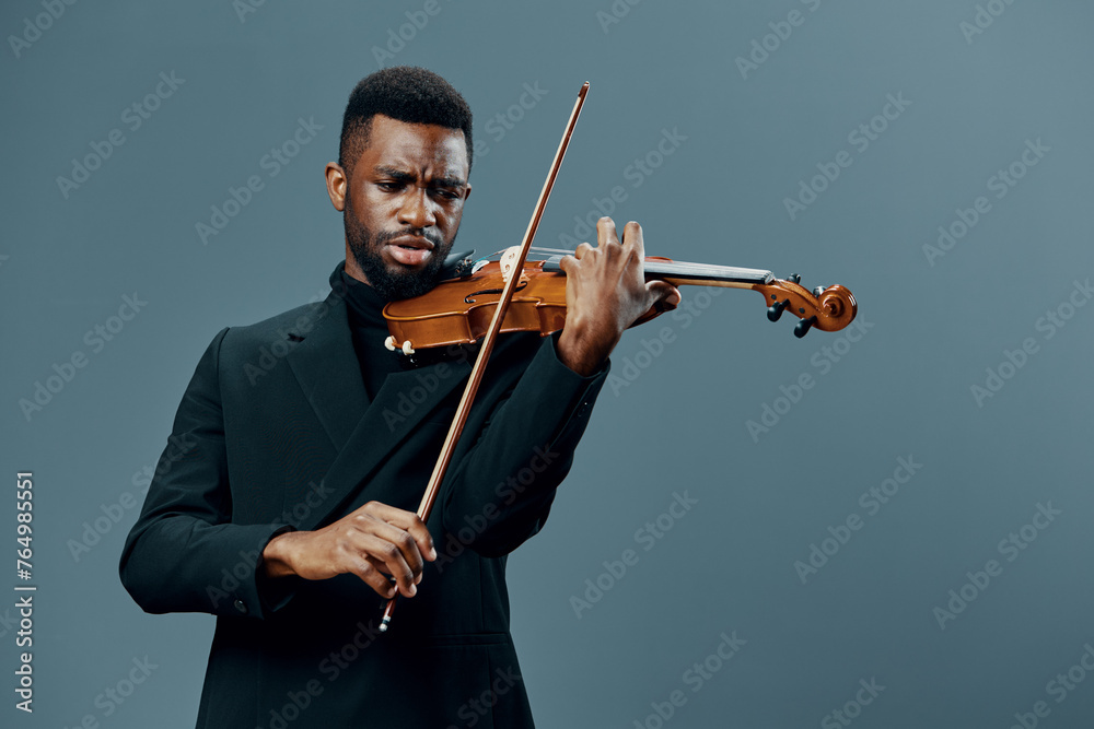 Elegant black violinist in a formal suit performing on violin against a ...