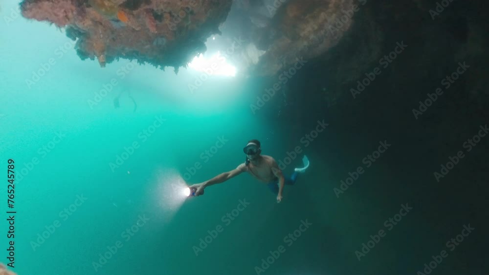 Raja Ampat freediving. Man freediver swims underwater with torch and ...