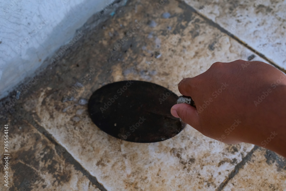 A hand scraping a cement stain on the floor. A worker is scraping the ...