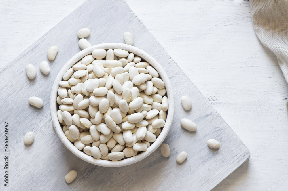 Uncooked dried white haricot beans in bowl or spoon on table. Heap of ...