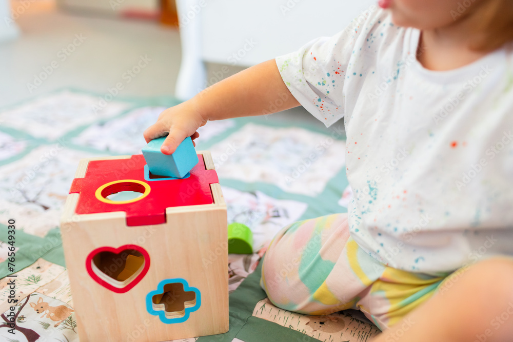 Toddler posting coloured shapes into wooden shape sorter box Stock ...