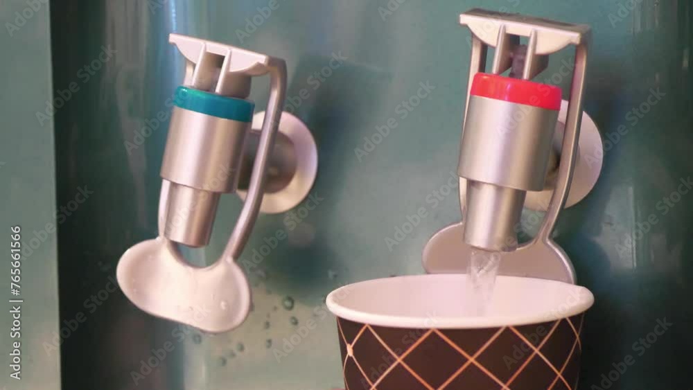 Male hand holding paper cup and pouring hot and cold water from cooler ...