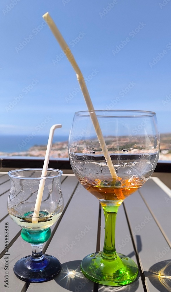 Pair of cocktail glasses with biodegradable straw, on panoramic sea ...