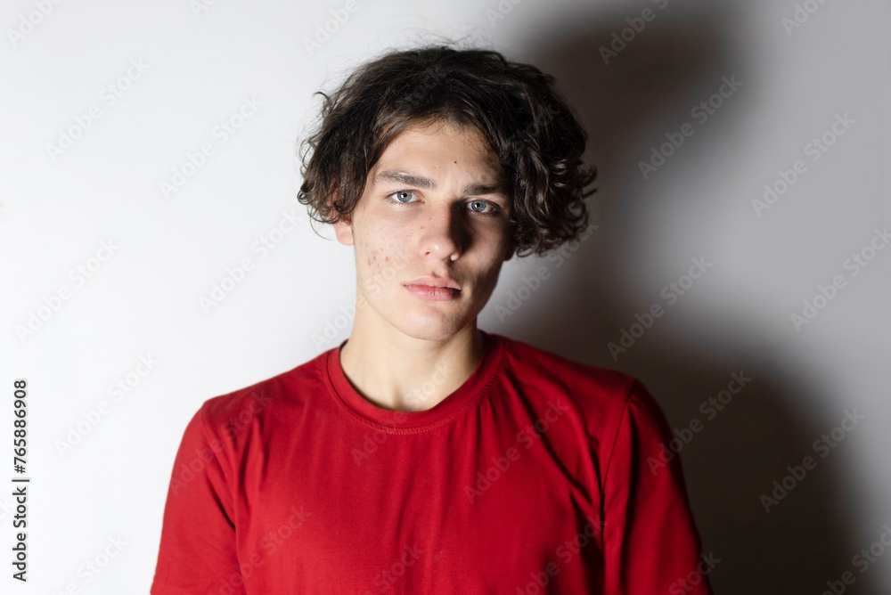 Teenage boy with long hair in a red t-shirt with red pimples on his ...