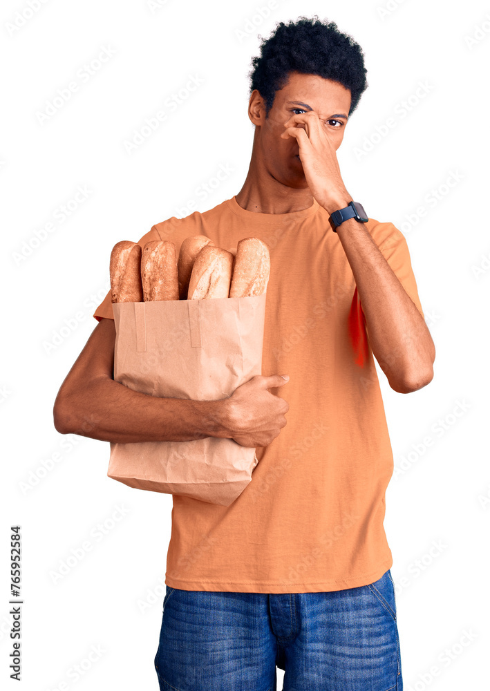 Young african american man holding paper bag with bread smelling ...