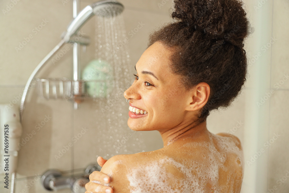 Chin raised, eyebrows raised, jaw relaxed, happy smile as she showers ...