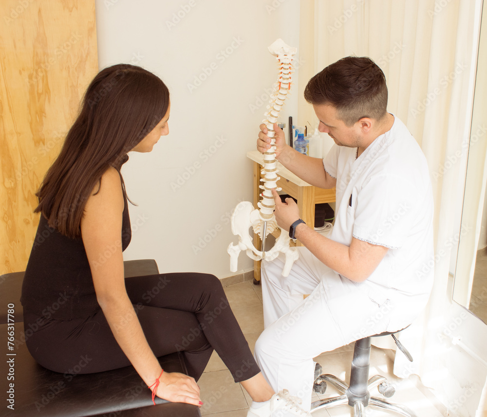 A male osteopath explaining to his female patient about a lumbar disc ...