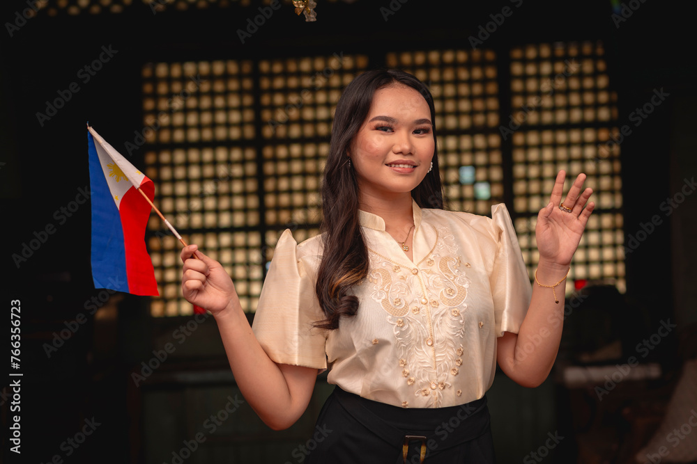 Portrait of a young tour guide holding a Philippine flag, dressed in ...