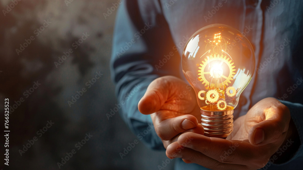 Human hands holding a glowing light bulb with gears inside ...