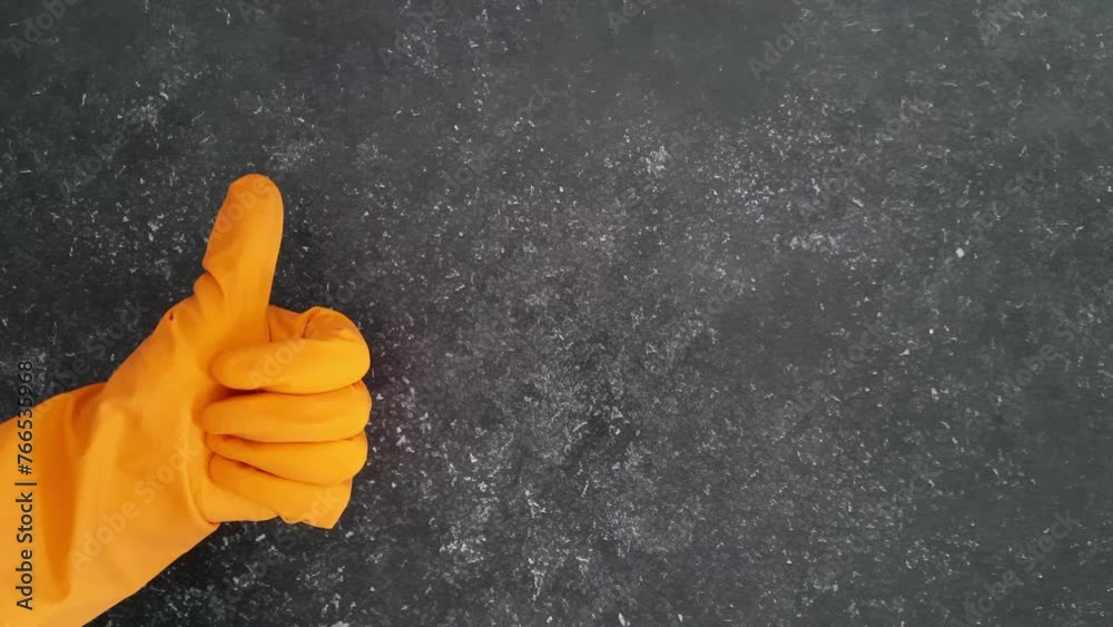 Thumbs up gesture on dark background. Hand in orange rubber cleaning ...
