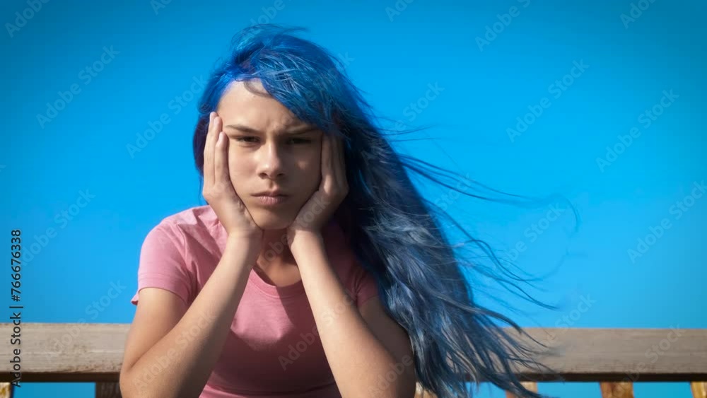 Sad teenager with blue hair. A sad young girl sits thoughtfully on a ...
