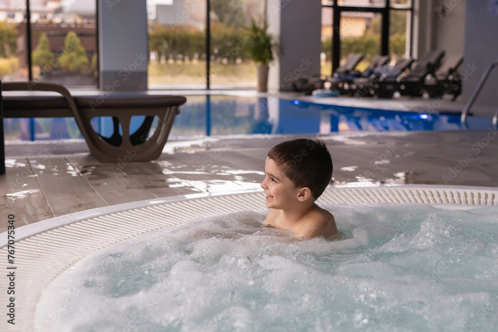 Boy sitting in the warm bubbling water jacuzzi. Happy kid relaxing in ...