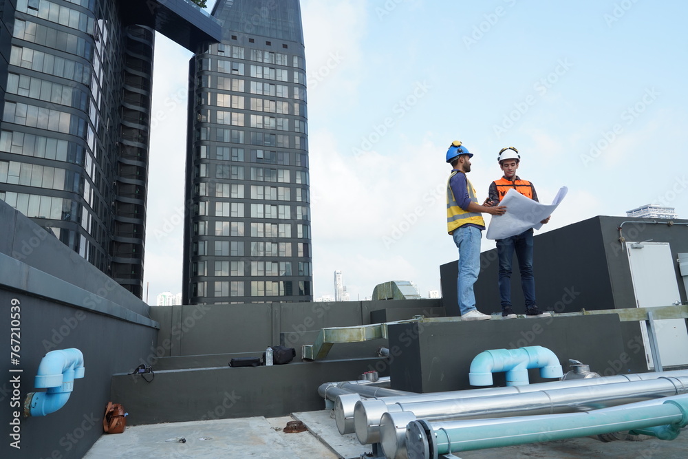 Foreman engineer wearing reflective jacket, hard hat, standing holding ...