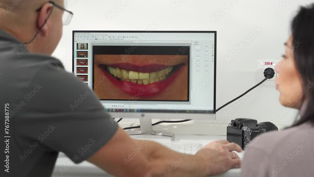 Cosmetic dentist shows photo of teeth smile to female patient on screen ...