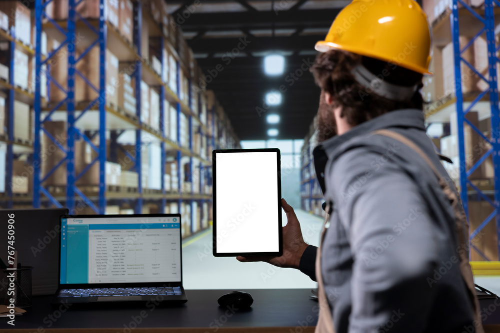 Depot worker examining stock checklist and tablet with white screen ...