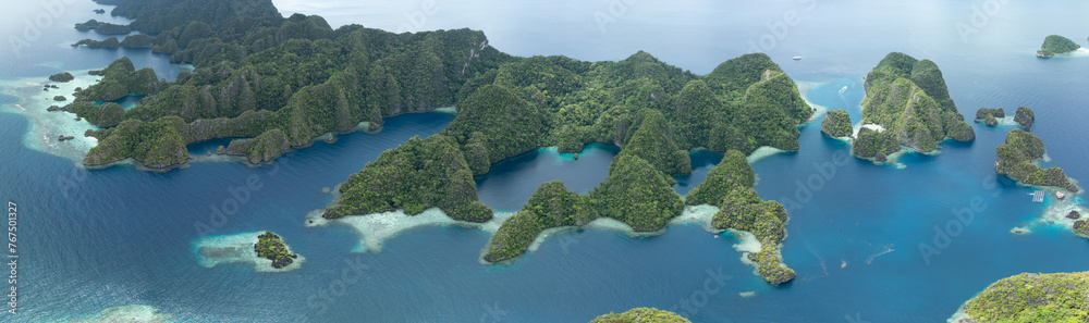 Rock islands, surrounded by coral reef, rise from Raja Ampat's tropical ...