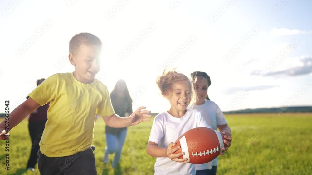 children playing rugby in the park. a group of children play american ...